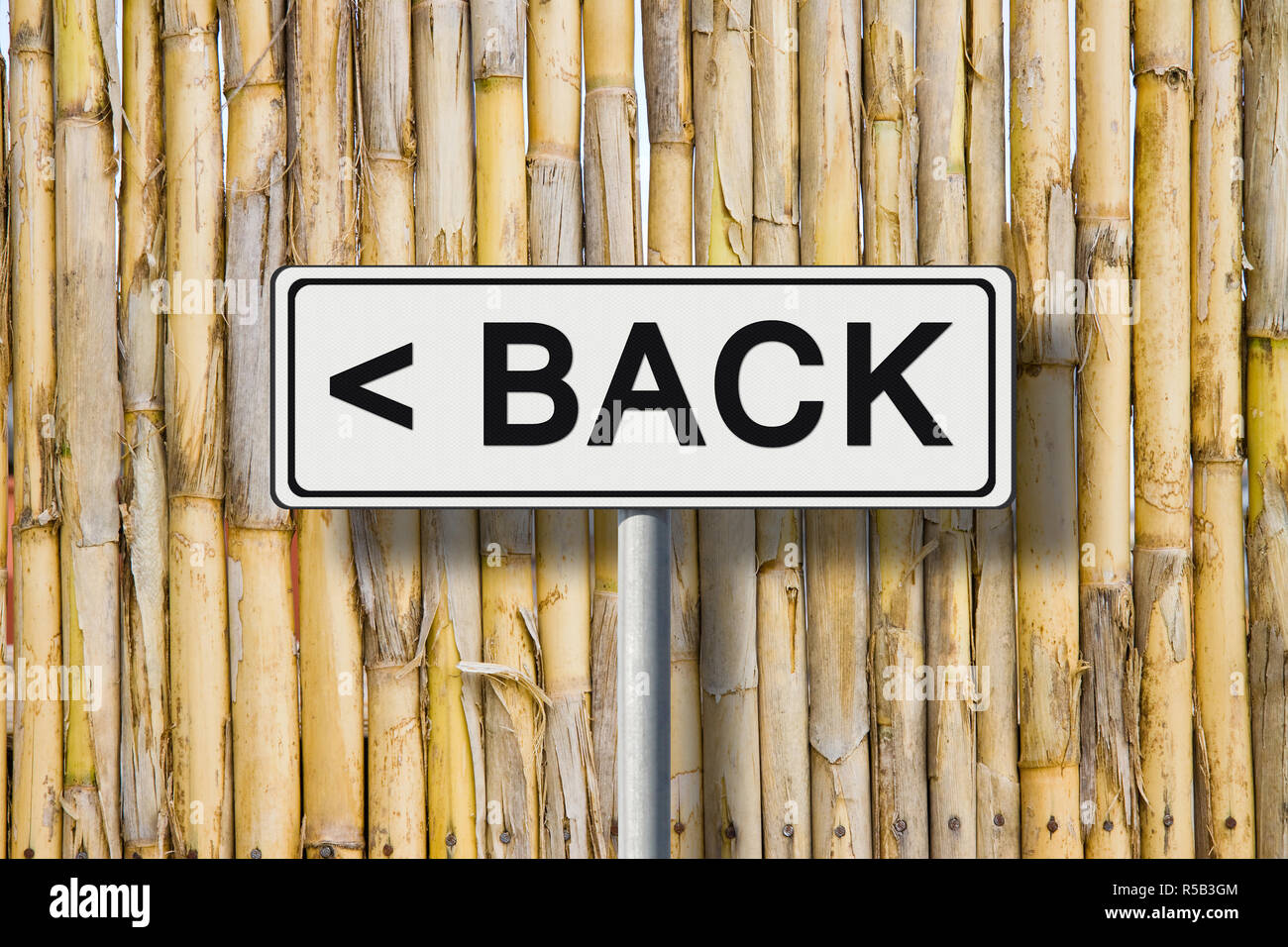 Le mot "Retour" écrit sur un panneau routier contre une clôture wattle ...