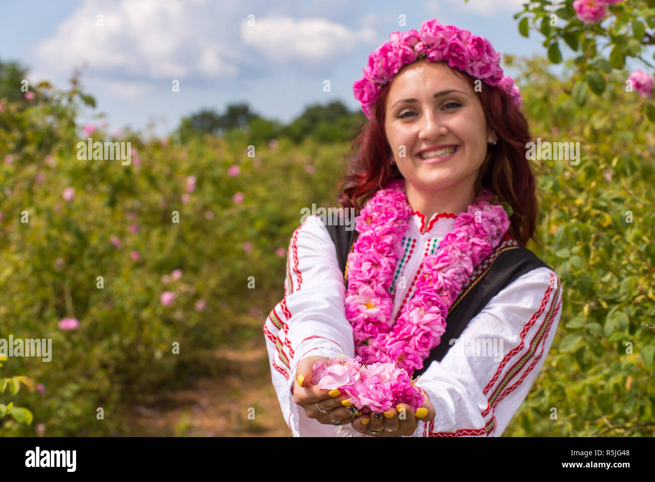 Fille bulgare habillés en vêtements traditionnels en donnant des roses ...