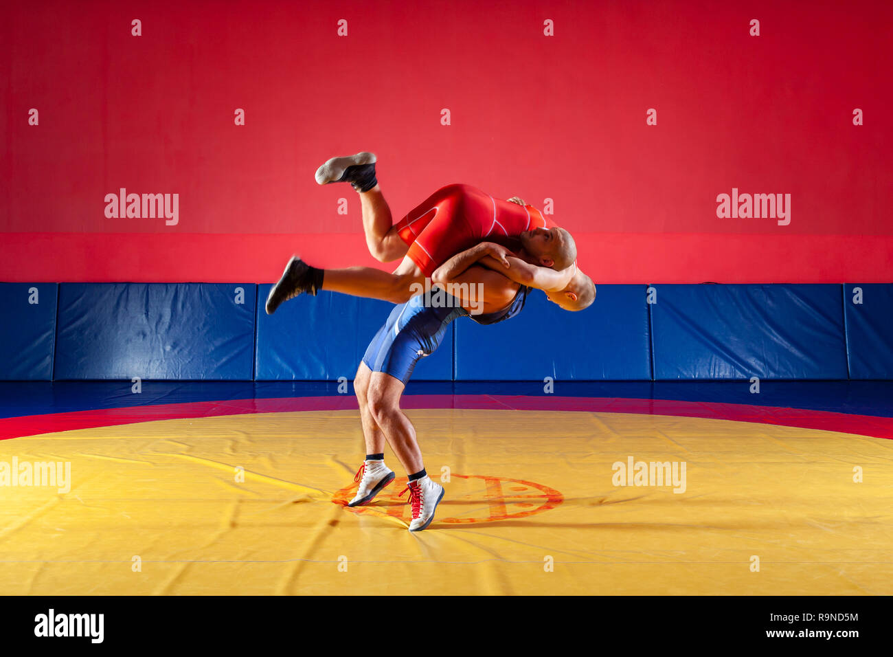 Deux lutteurs gréco-romain en uniforme rouge et bleu sur fond de lutte ...