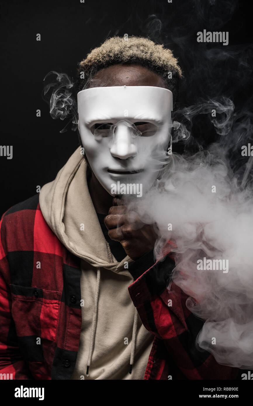 Jeune homme africain avec masque sur le visage vape cigarette ...