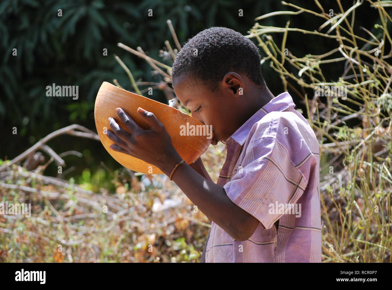 Un garçon Peul boire du lait à partir d'un bol de calebasse au Niger ...