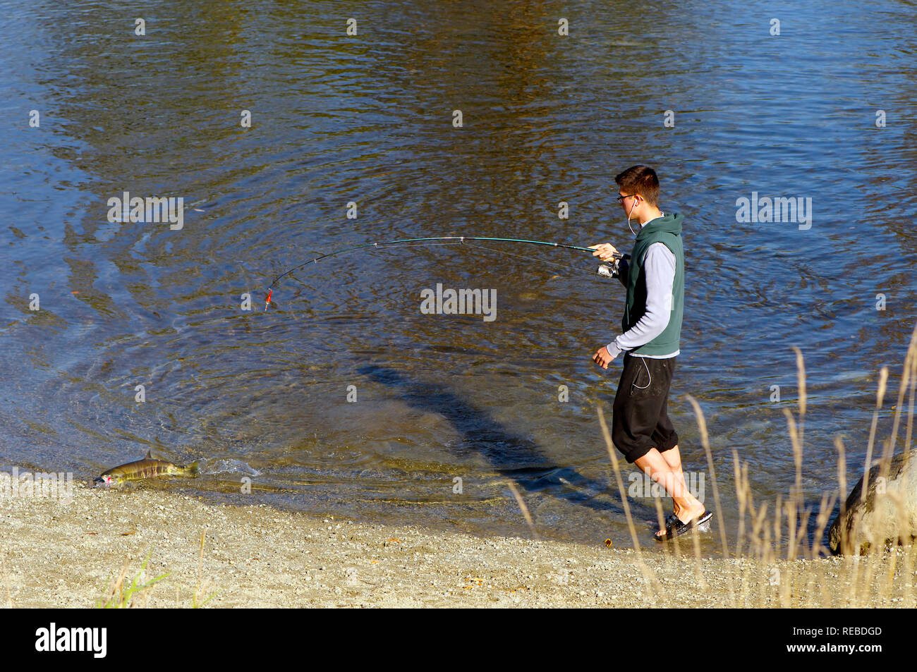 Adolescent avec la canne à pêche et un poisson sur la rive de la ...