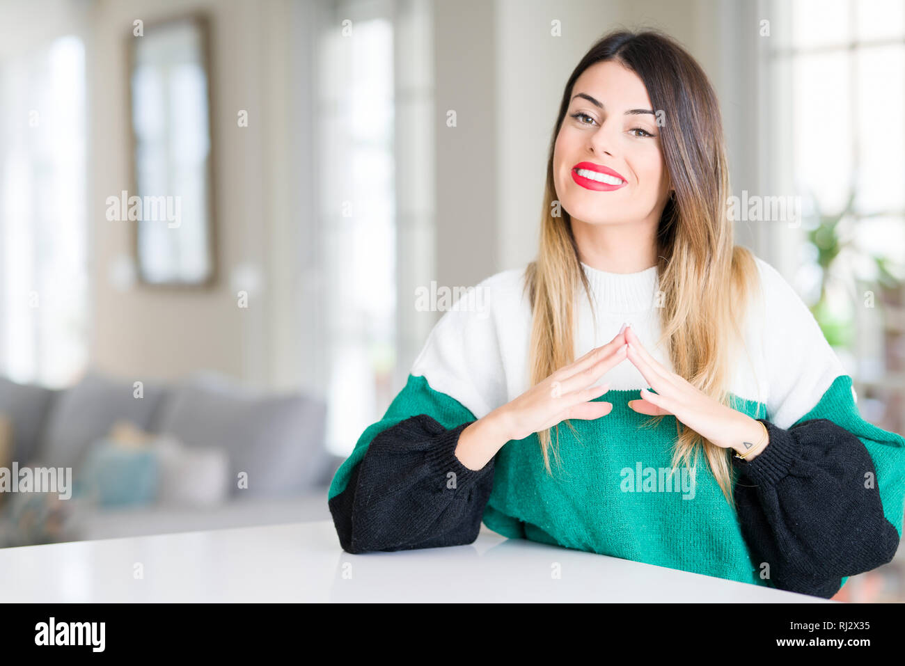 Belle Jeune femme portant le chandail d'hiver à la maison les mains et ...
