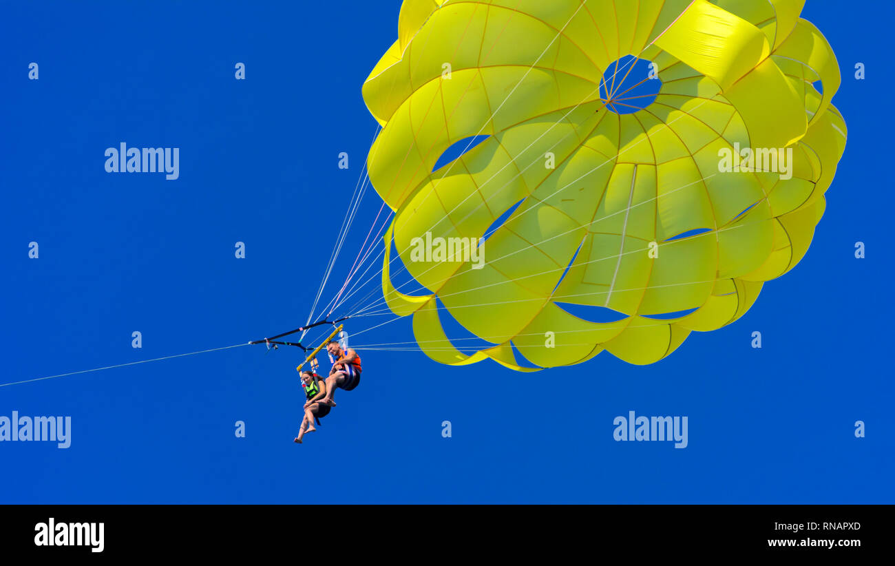 Un parachutiste vole avec un parachute coloré attaché à un bateau sur ...