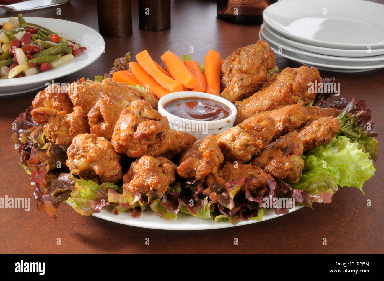 Une partie plateau avec des ailes de poulet et des bâtonnets de carotte ...