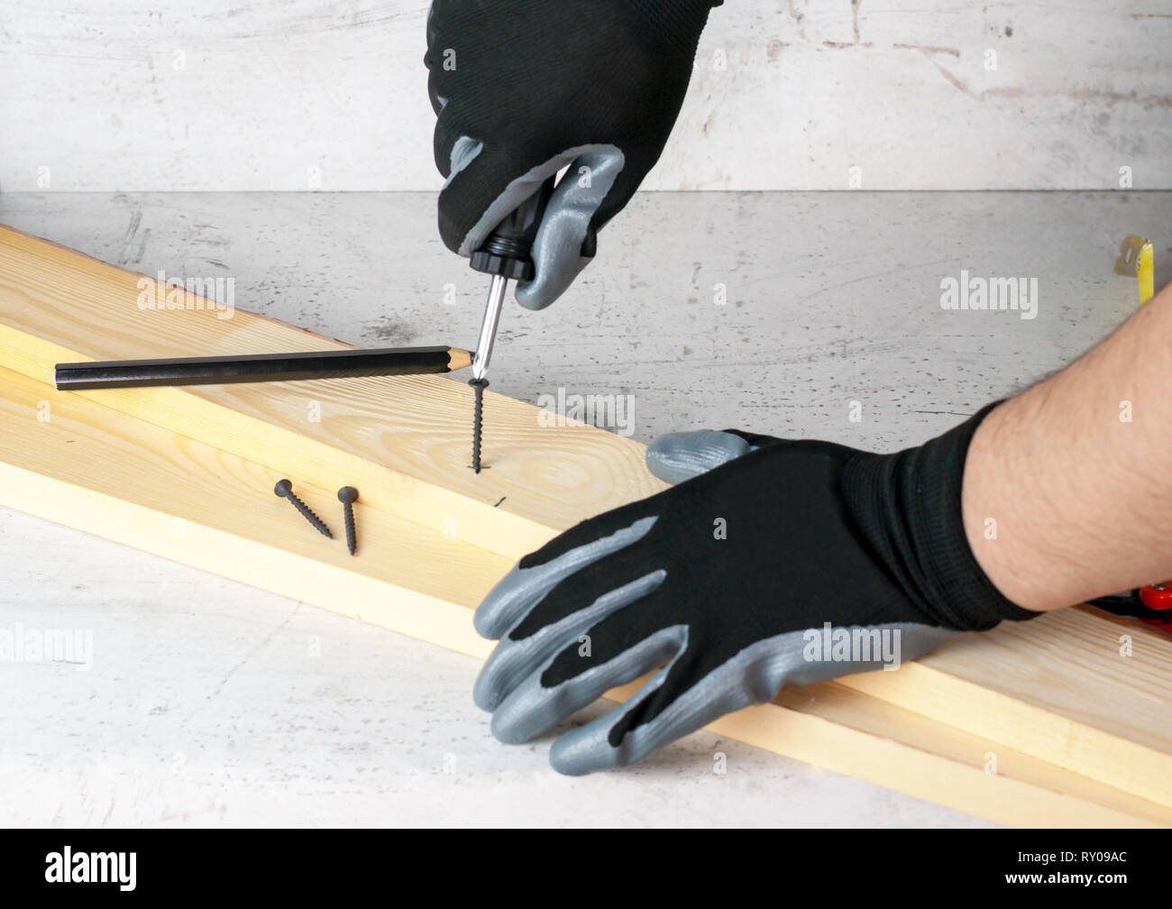Un homme met des repères sur les barres en bois pour plus de vissage de ...