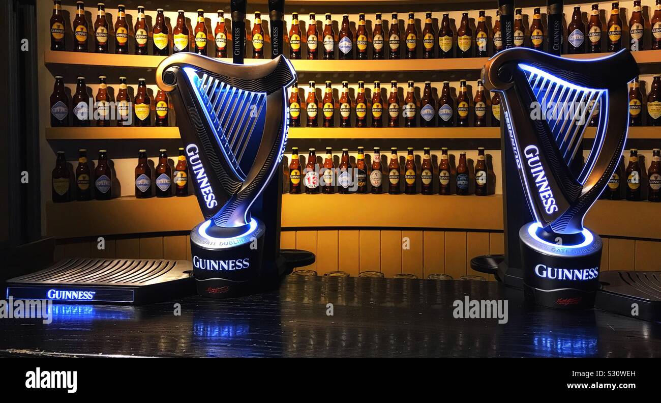 Pompes à bière Guinness dans un bar avec des bouteilles de Guinness sur ...