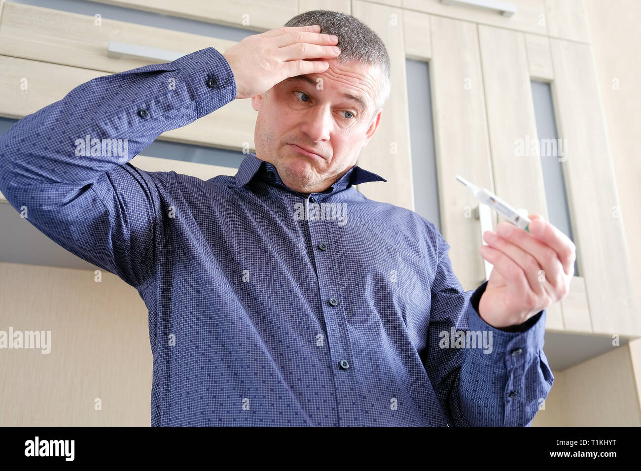 Un homme tenant un thermomètre dans ses mains, la mesure de la ...