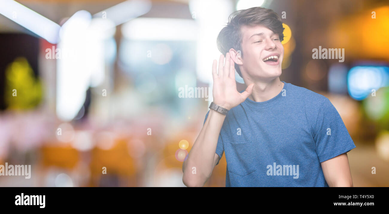 Beau jeune homme portant un tee-shirt bleu sur fond isolé smiling with ...