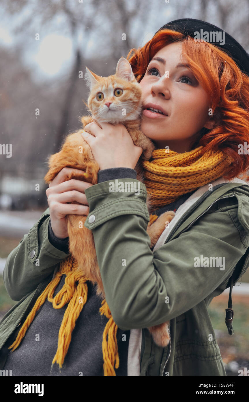 Portrait d'une jeune fille rousse avec un chat rouge en plein air, sur ...