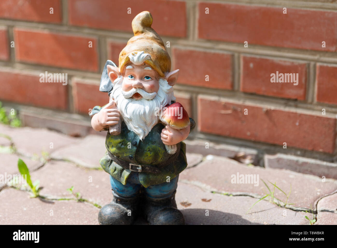 La figure d'un nain de jardin contre un mur de brique rouge. Close-up ...
