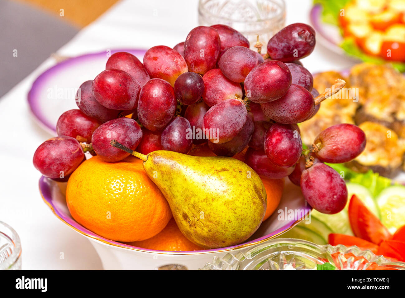 Des fruits dans une assiette sur la table. Grappe de raisin, de poire ...
