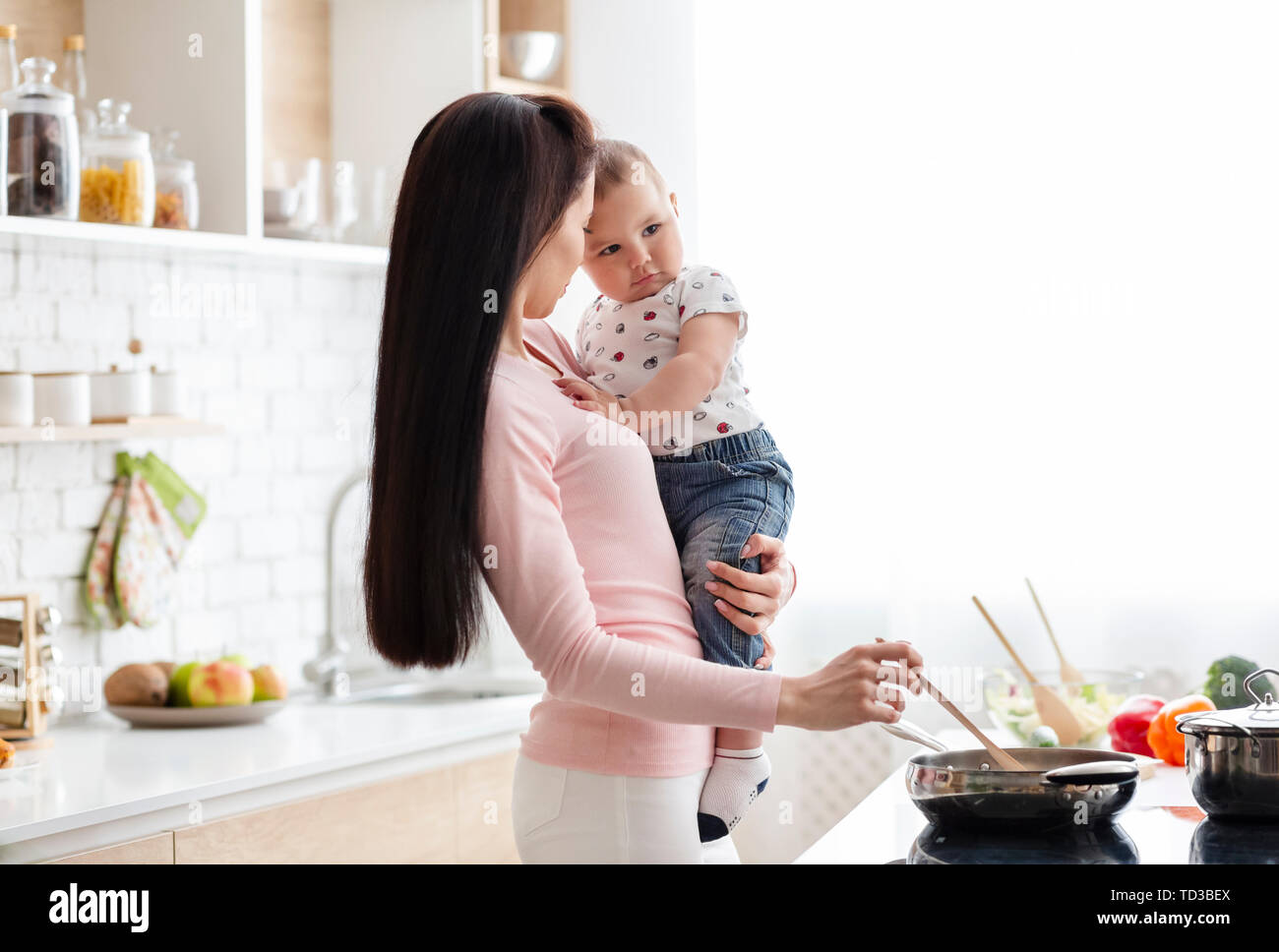Jeune femme avec bébé la cuisson dans la cuisine Photo Stock - Alamy
