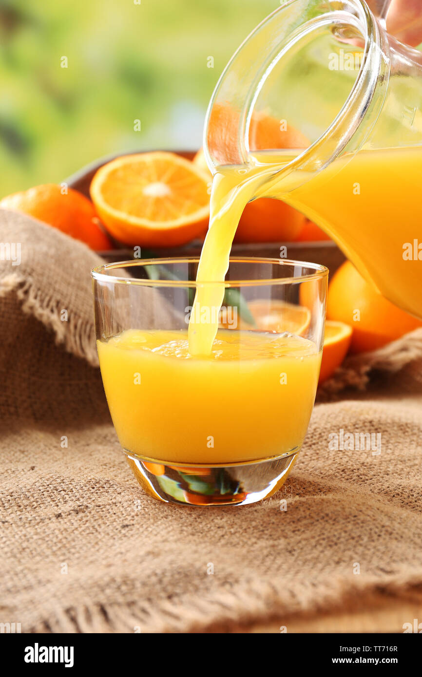 Verser le jus d'orange à partir de la carafe en verre, sur la table de ...