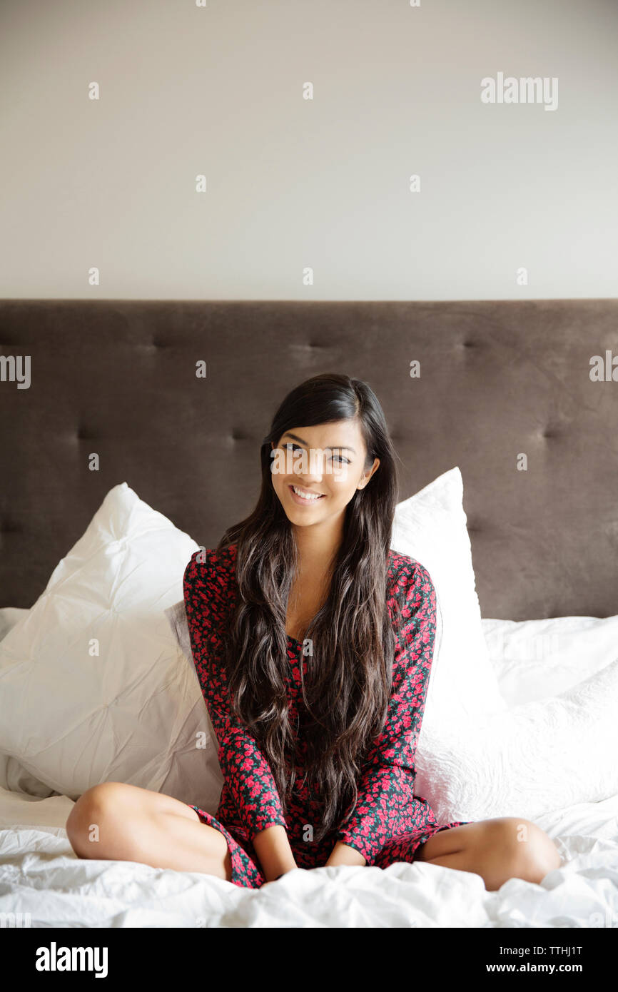 Jeune Femme Assise En Tailleur Sur Le Lit Banque De Photographies Et D