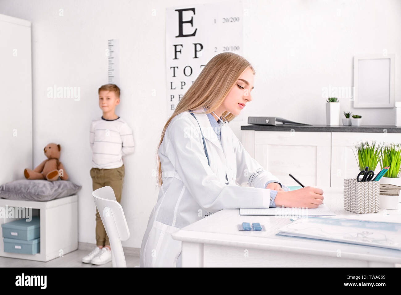 Jeune femme médecin écrire les résultats après la mesure de la hauteur ...
