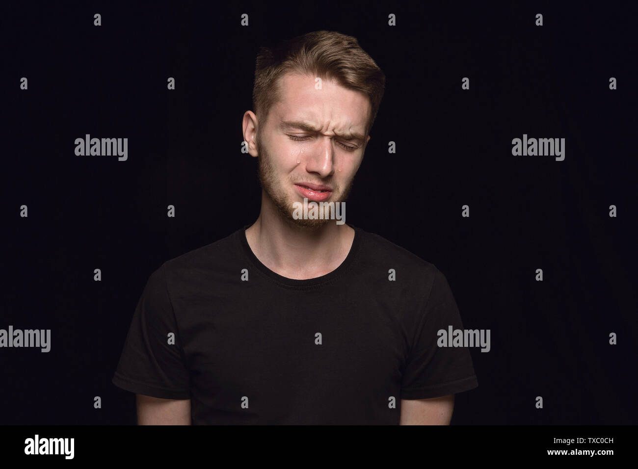 Close up portrait of young man isolé sur fond de studio noir. De ...