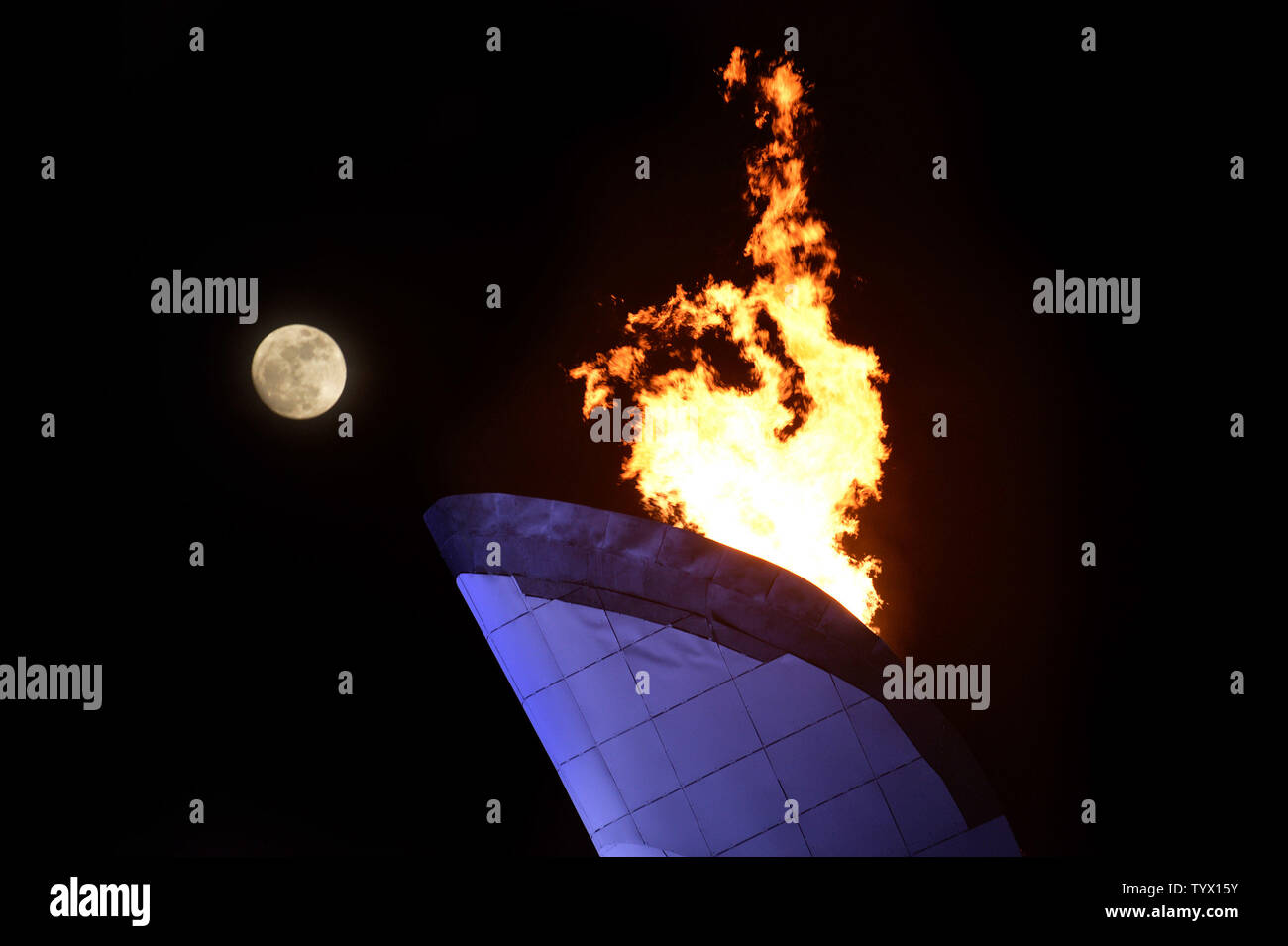 Une presque pleine lune se lève derrière la vasque olympique lors des ...