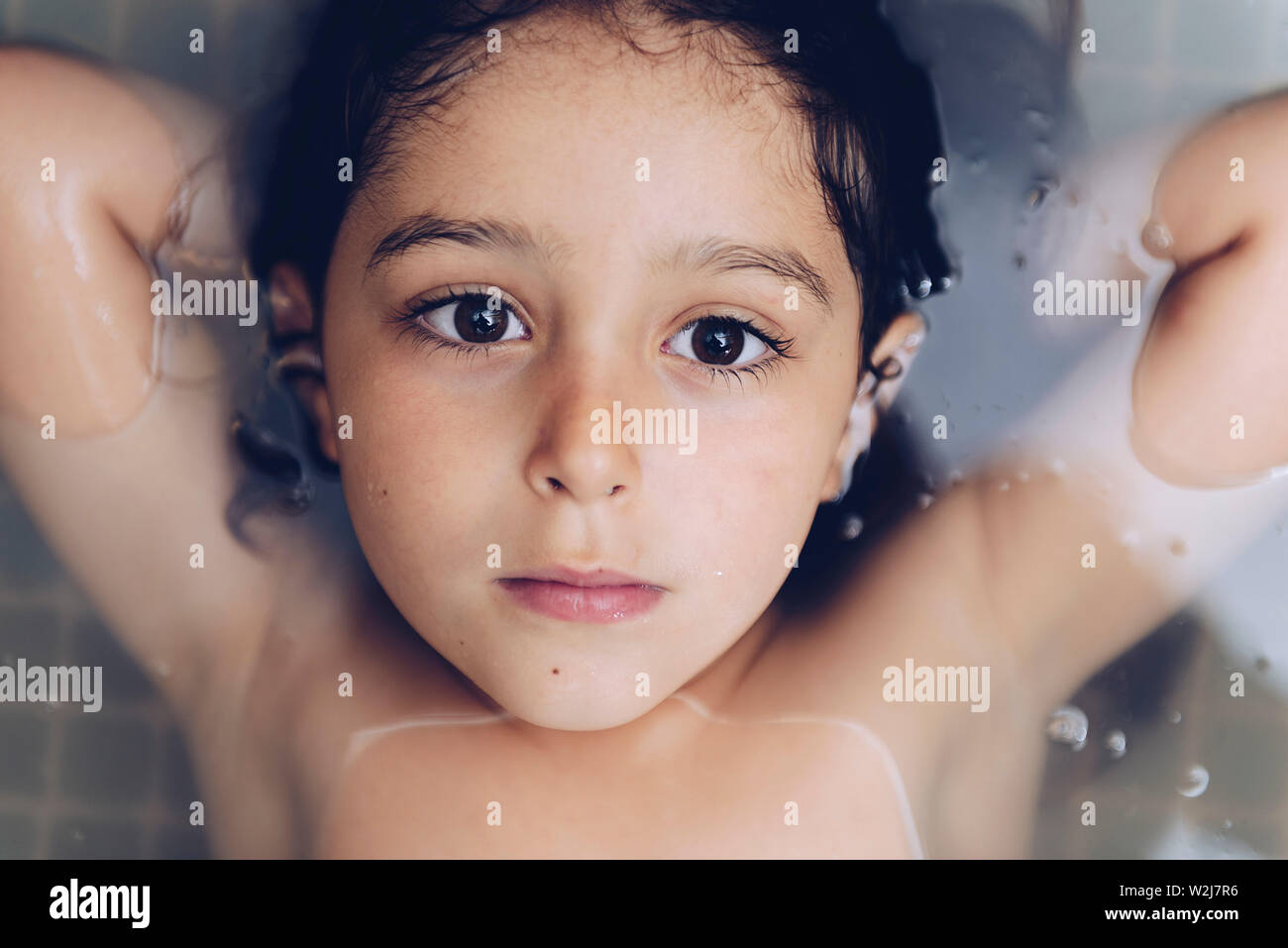 Portrait of a happy pretty little girl couché dans la baignoire tout en ...