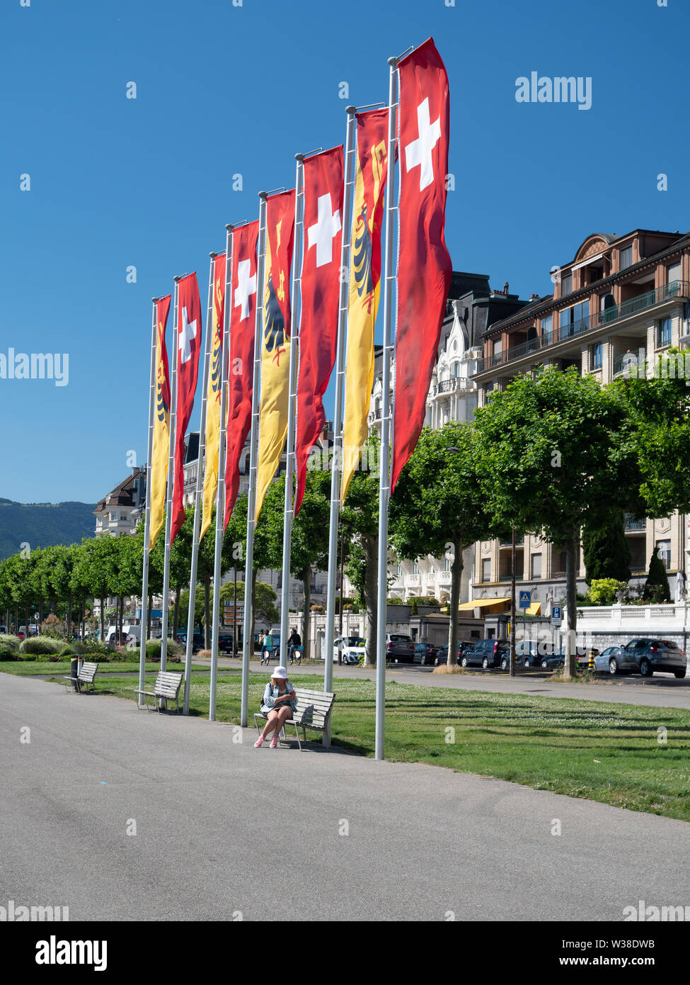 Un touriste assis sous les drapeaux de Genève et Suisse drapeaux qui ...