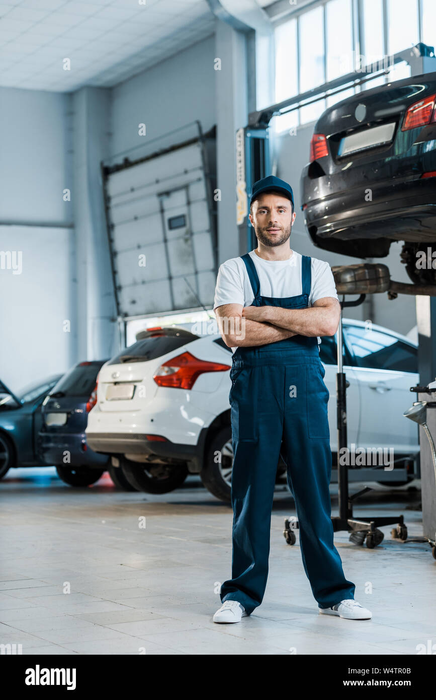 Beau mécanicien de voiture debout les bras croisés près des voitures Photo Stock - Alamy