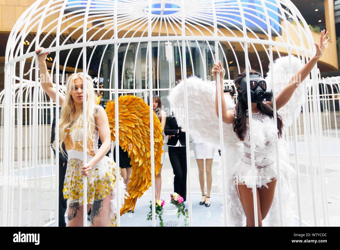 Artistes portant des ailes sont confinés dans des cages d'oiseaux lors ...