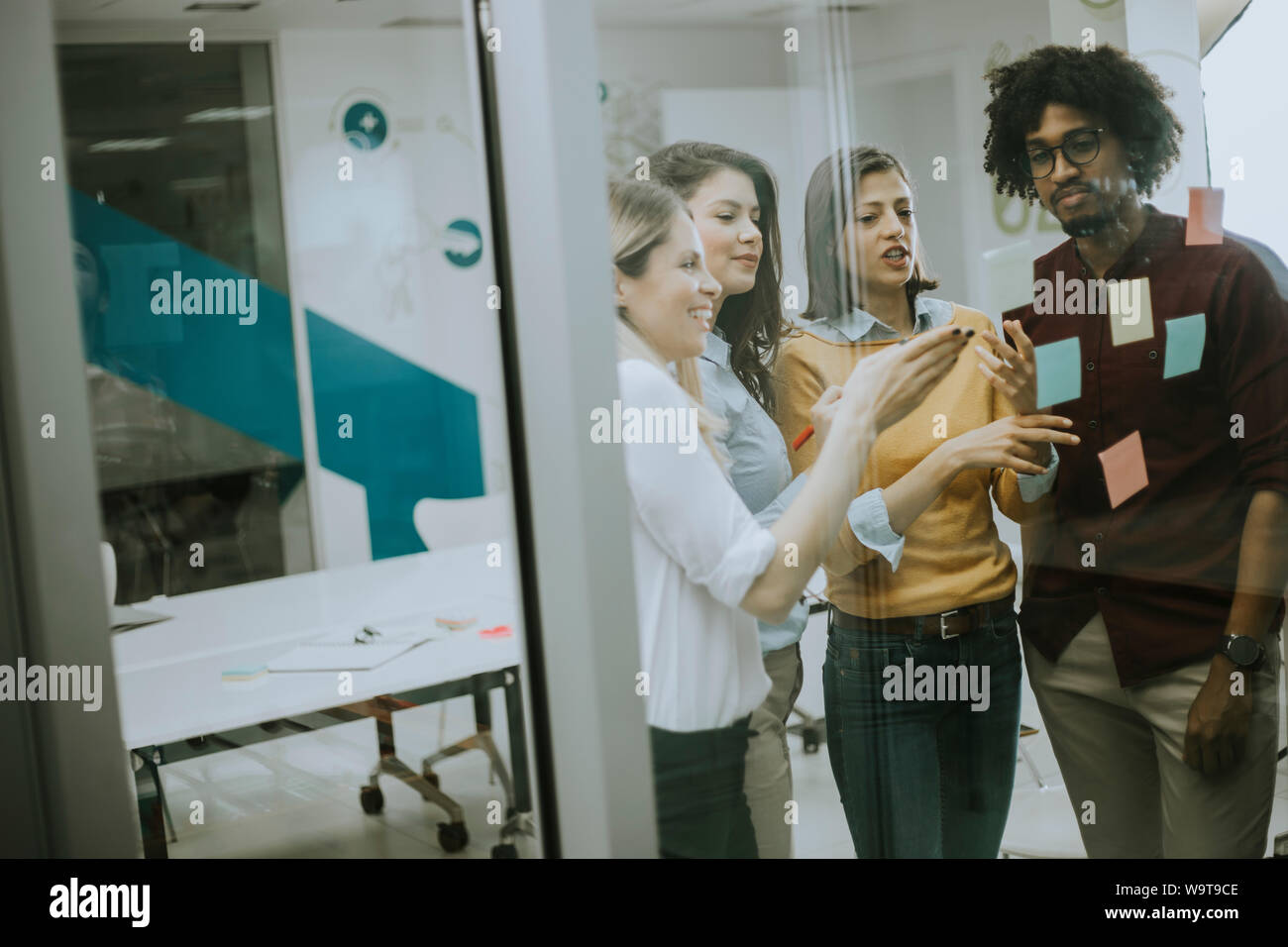 Groupe de jeunes gens d'affaires de discuter en face du mur de verre à ...