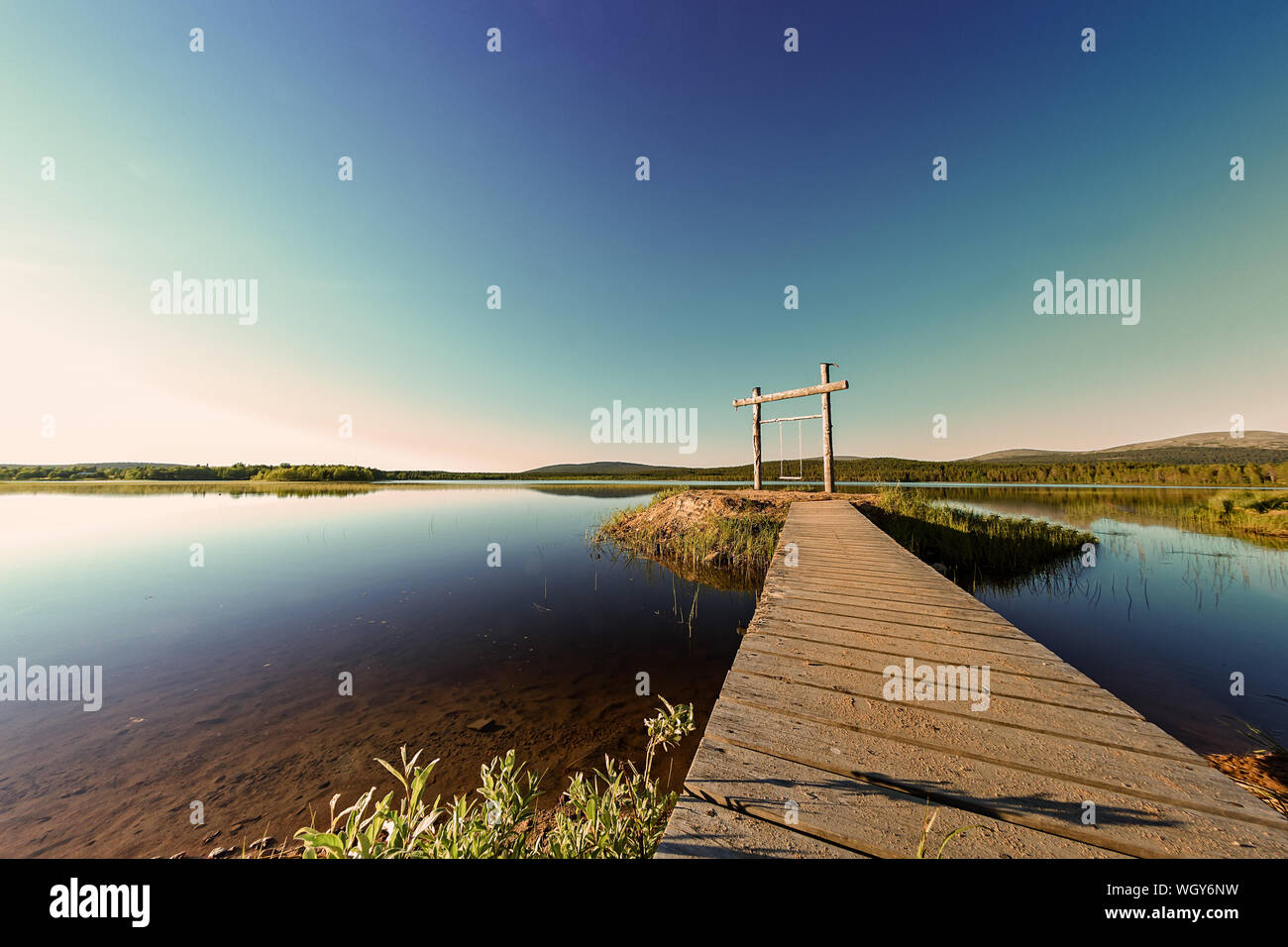 Le pont qui mène à un swing au bord d'un lac dans la Laponie ...