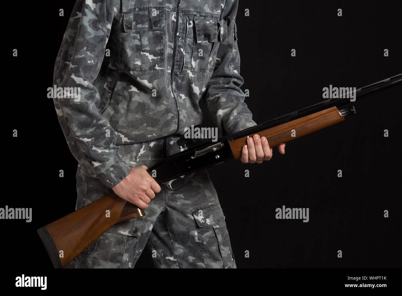 Un homme avec une arme à feu dans l'uniforme militaire de camouflage ...