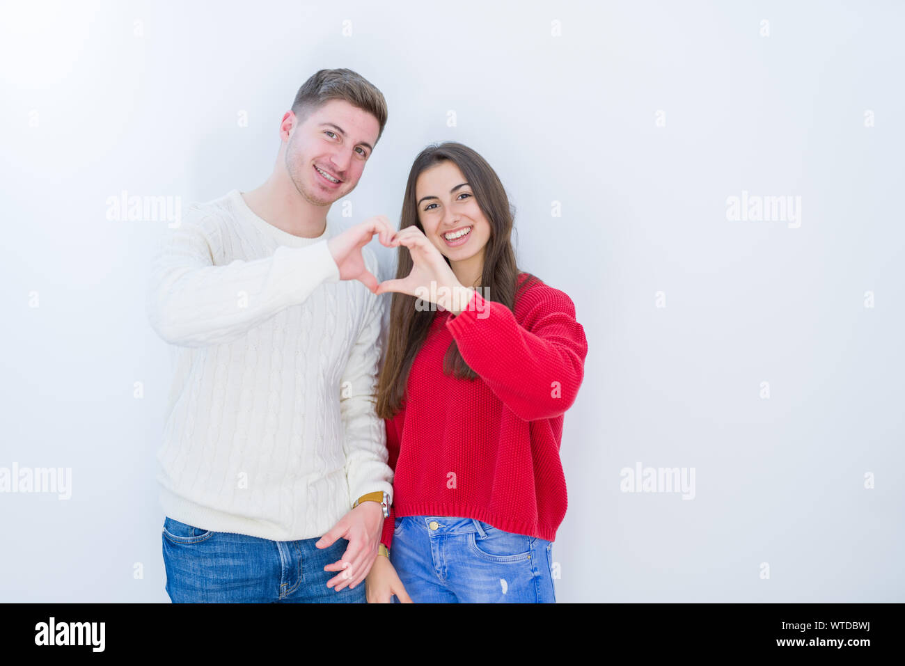 Beau jeune couple over white background isolés dans l'amour sourire ...
