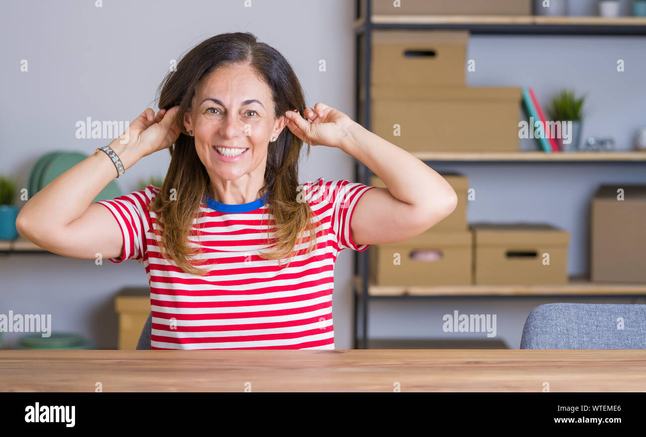 L'âge moyen des hauts femme assise à la table à la maison sourire ...