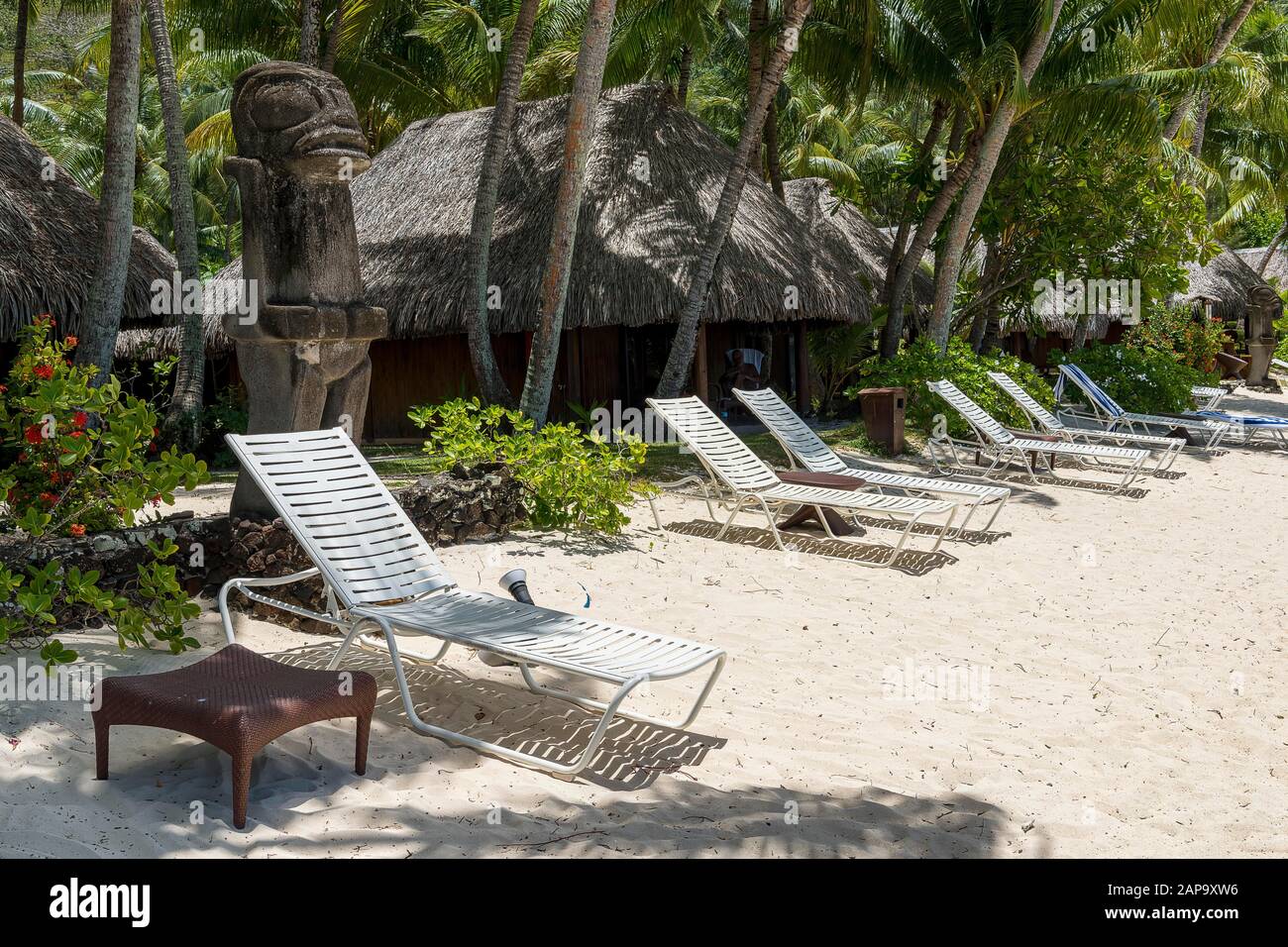 Scultura Polinesiana e sdraio di fronte ai bungalow sulla spiaggia di ...