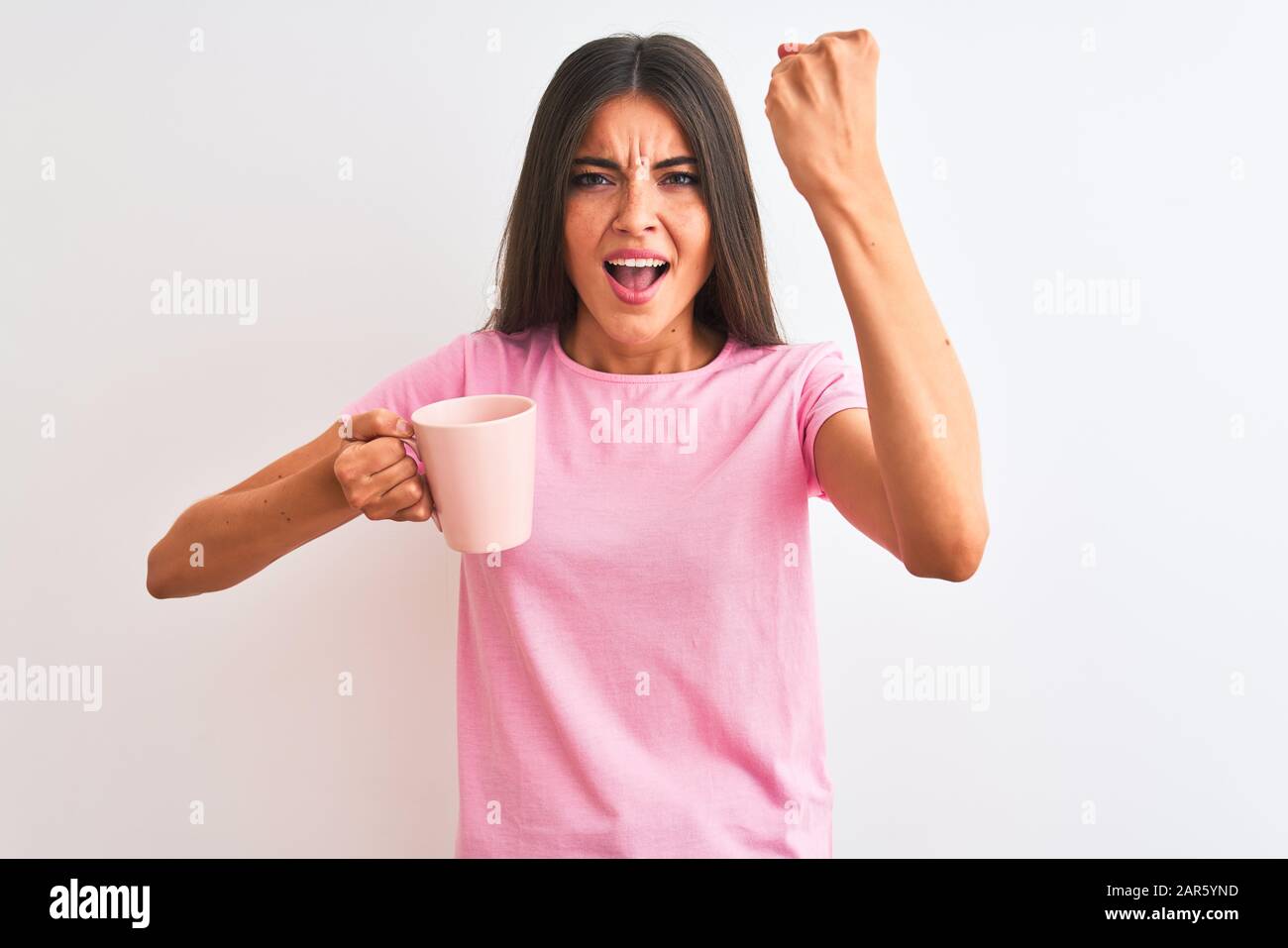 Giovane bella donna che beve tazza rosa di caffè in piedi su sfondo ...