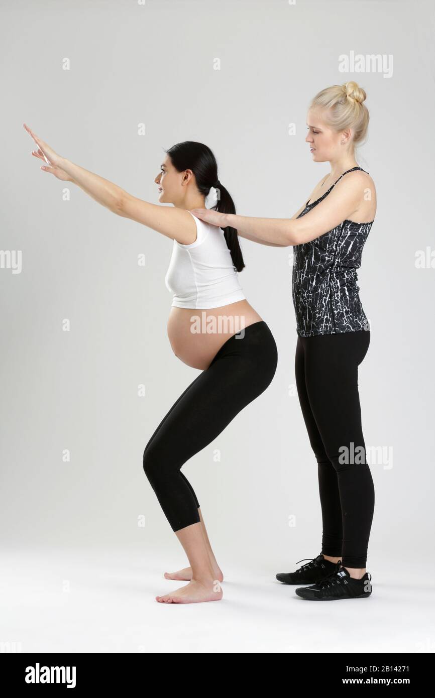 Donna incinta facendo esercizi di fitness con un personal trainer ...