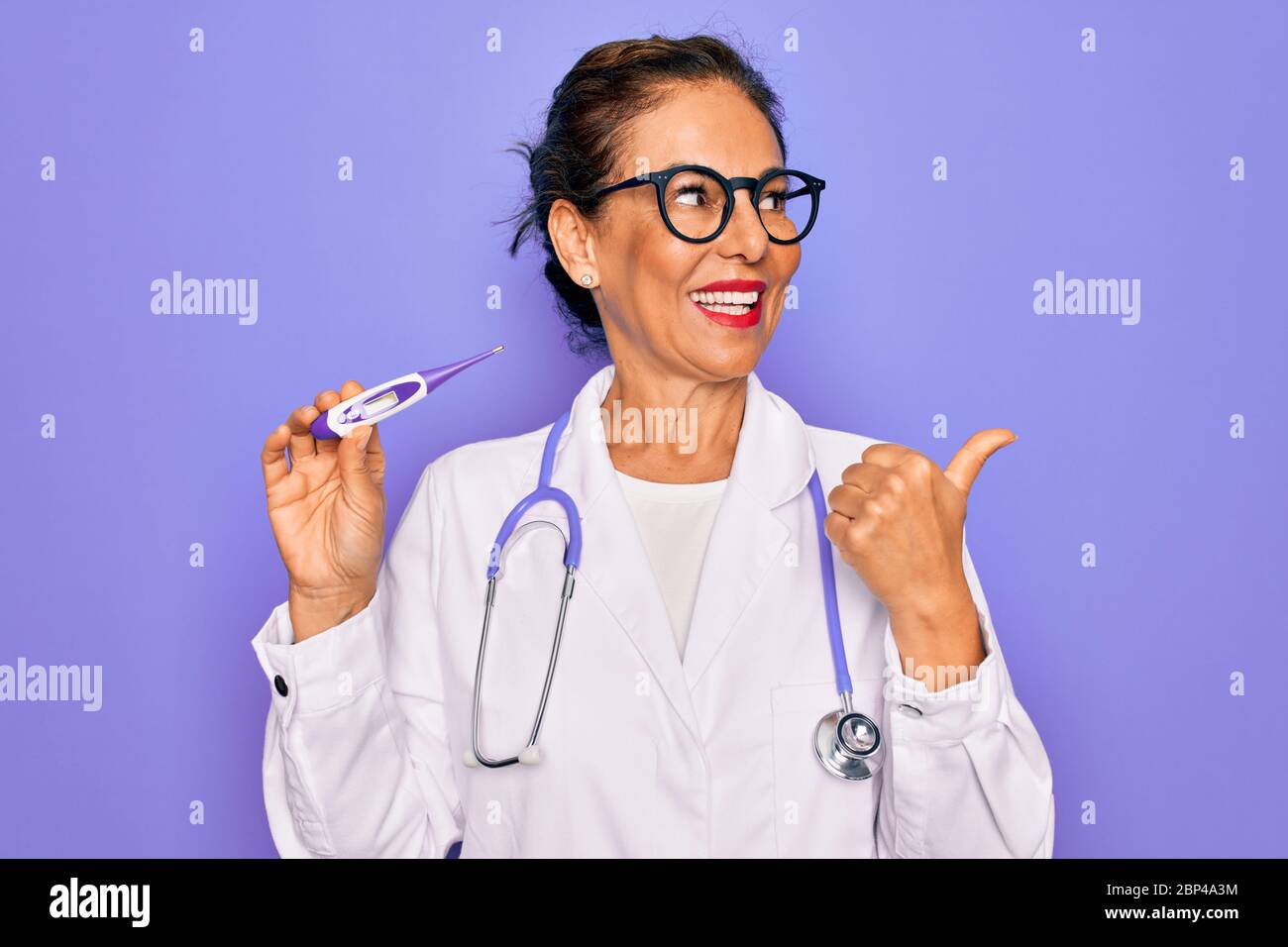 Donna medico professionale anziana di mezza età che tiene il termometro ...