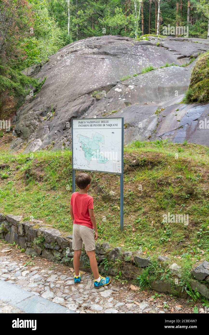 Giovane ragazzo che guarda le mappe esposte sul cartello, Parco Nazionale Naquane delle ...