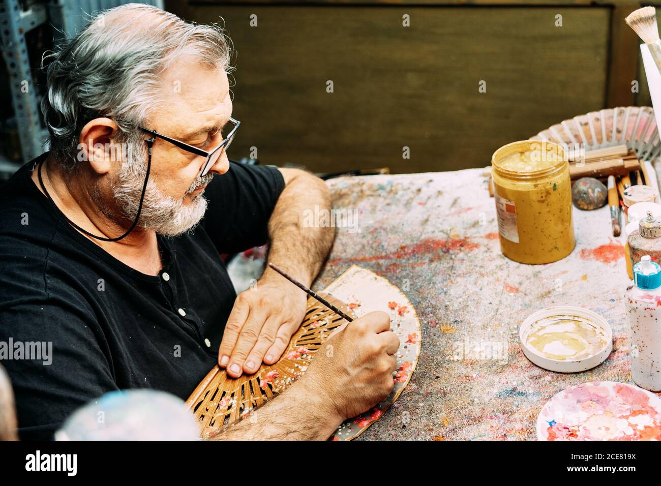 Pittore con pennello per disegnare sulla mano ventilatore mentre si è ...