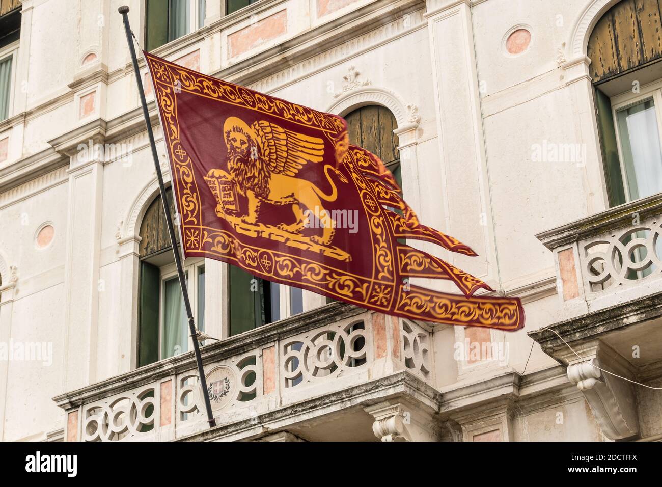 Bandiera di Venezia con leone alato e antico edificio veneziano sullo ...
