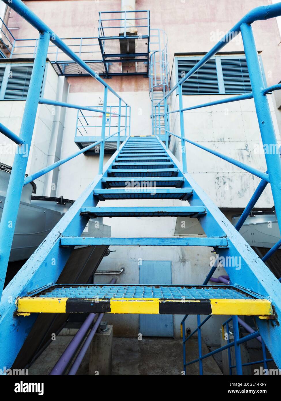 Scala industriale in metallo, con scalini e ringhiere blu e nastro di ...