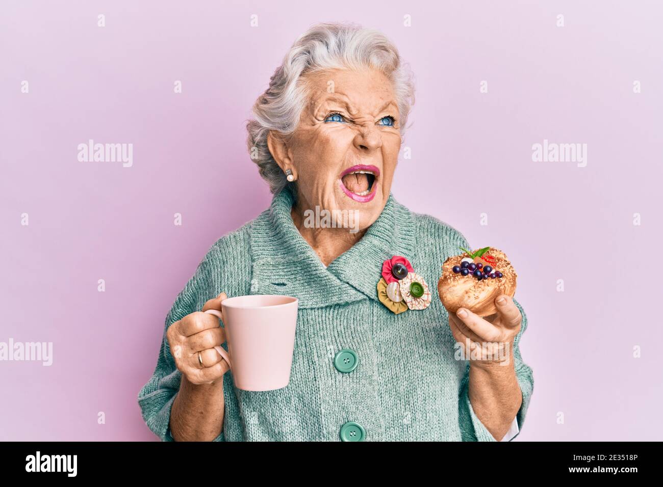 Donna anziana dai capelli grigi che beve una tazza di caffè e che ...