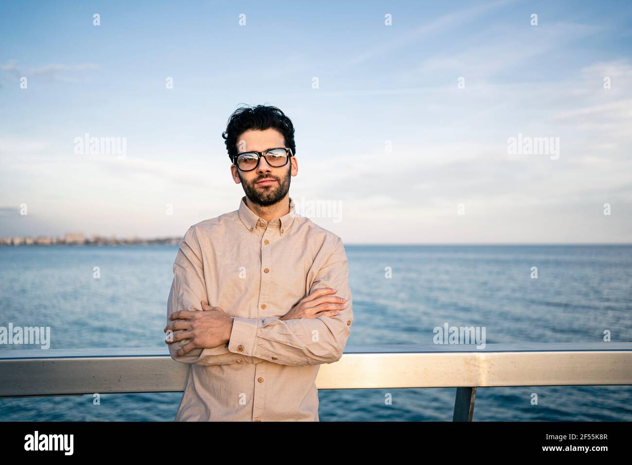 Uomo sorridente con le braccia incrociate in riva al mare immagini e ...