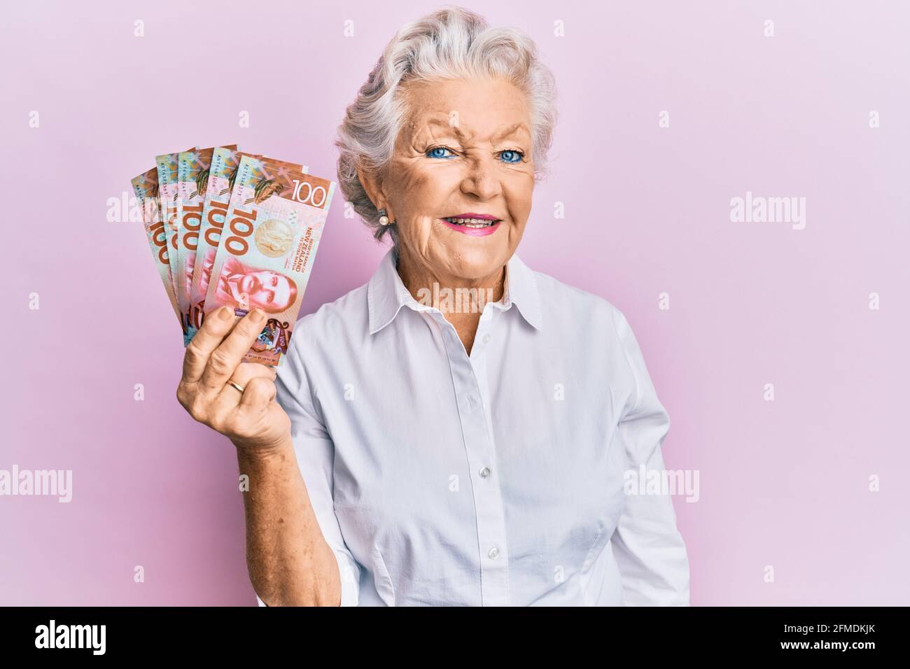 Donna anziana con capelli grigi che tiene in mano 100 banconote da ...