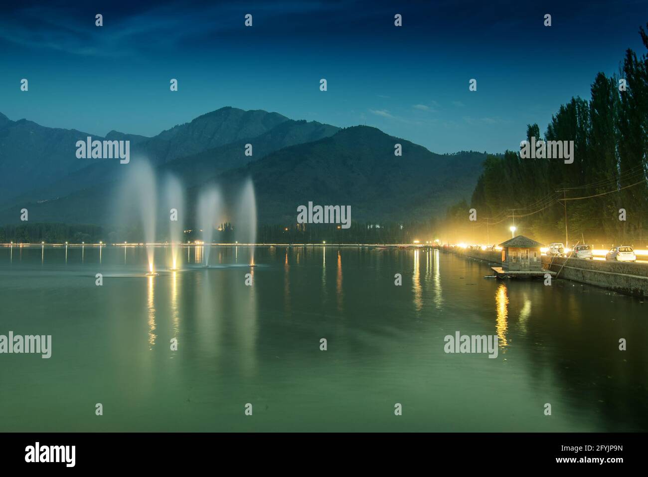 Fontane sul lago dal con le montagne sullo sfondo, al tramonto. Il lago ...