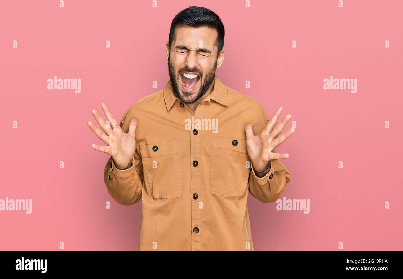 Giovane uomo ispanico che indossa abiti casual che celebra pazzo e ...
