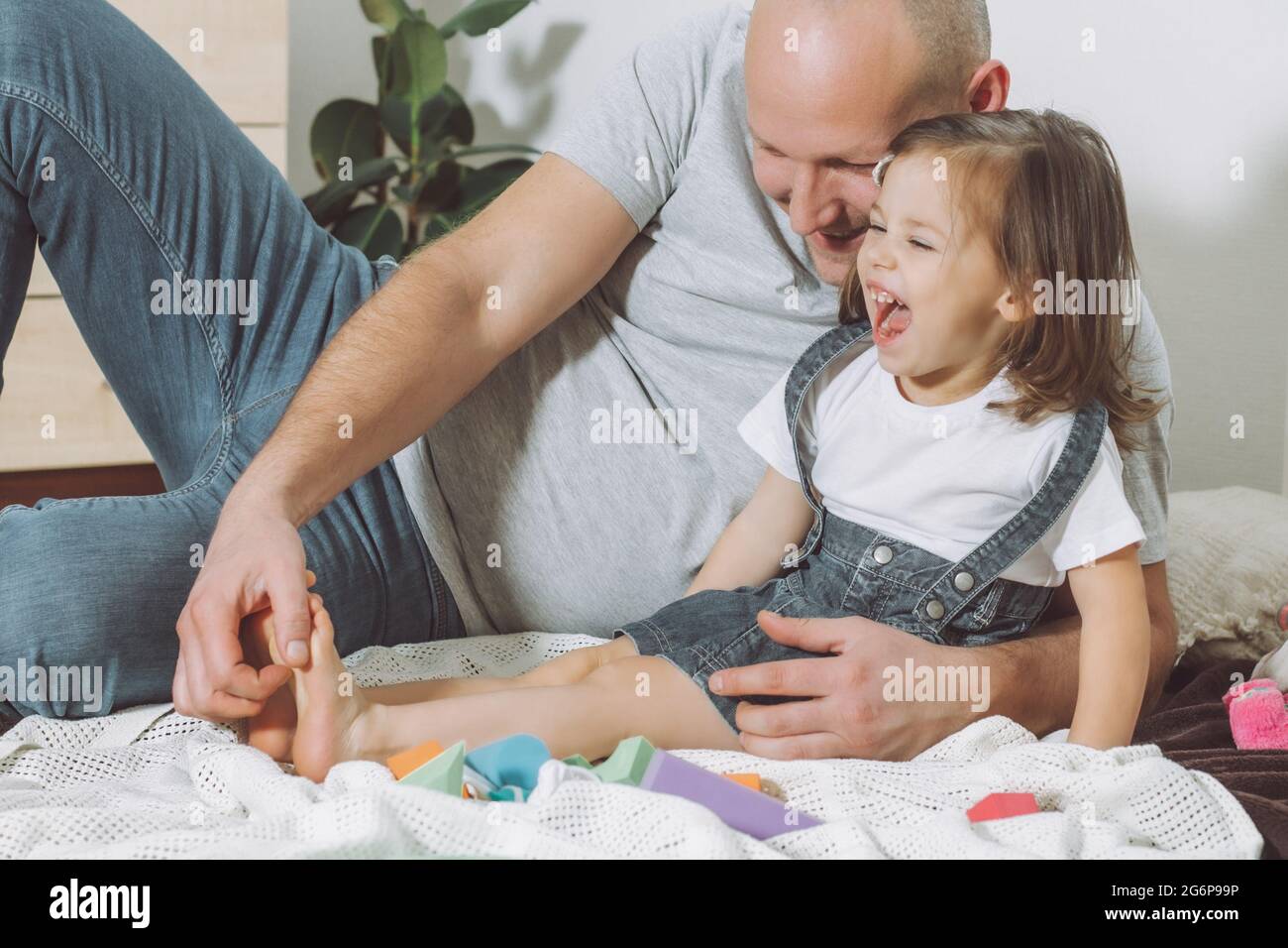 Padre gioca con la figlia piccola 2-4 sul pavimento. Papà solletico i ...