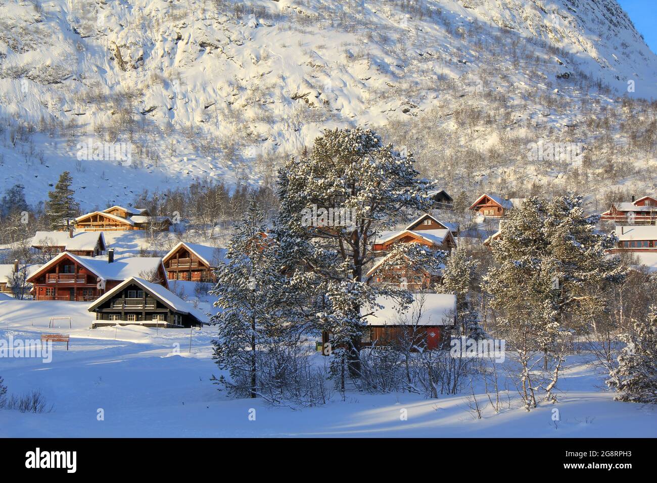 Villaggio di montagna sullo sfondo di montagne illuminate dal sole ...