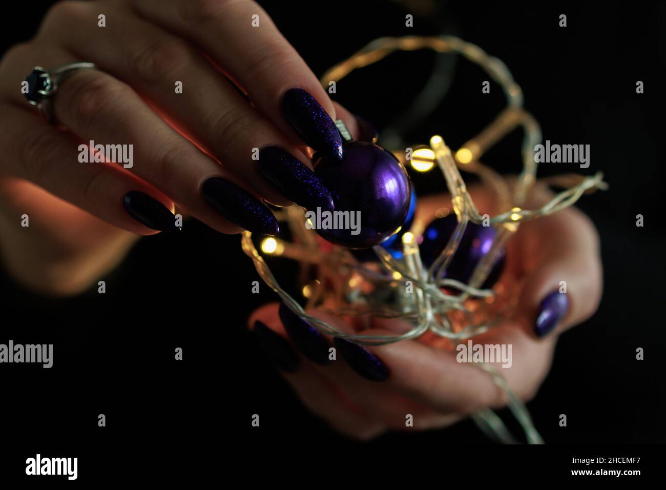Le mani femminili con le unghie lunghe e il manicure viola e blu ...