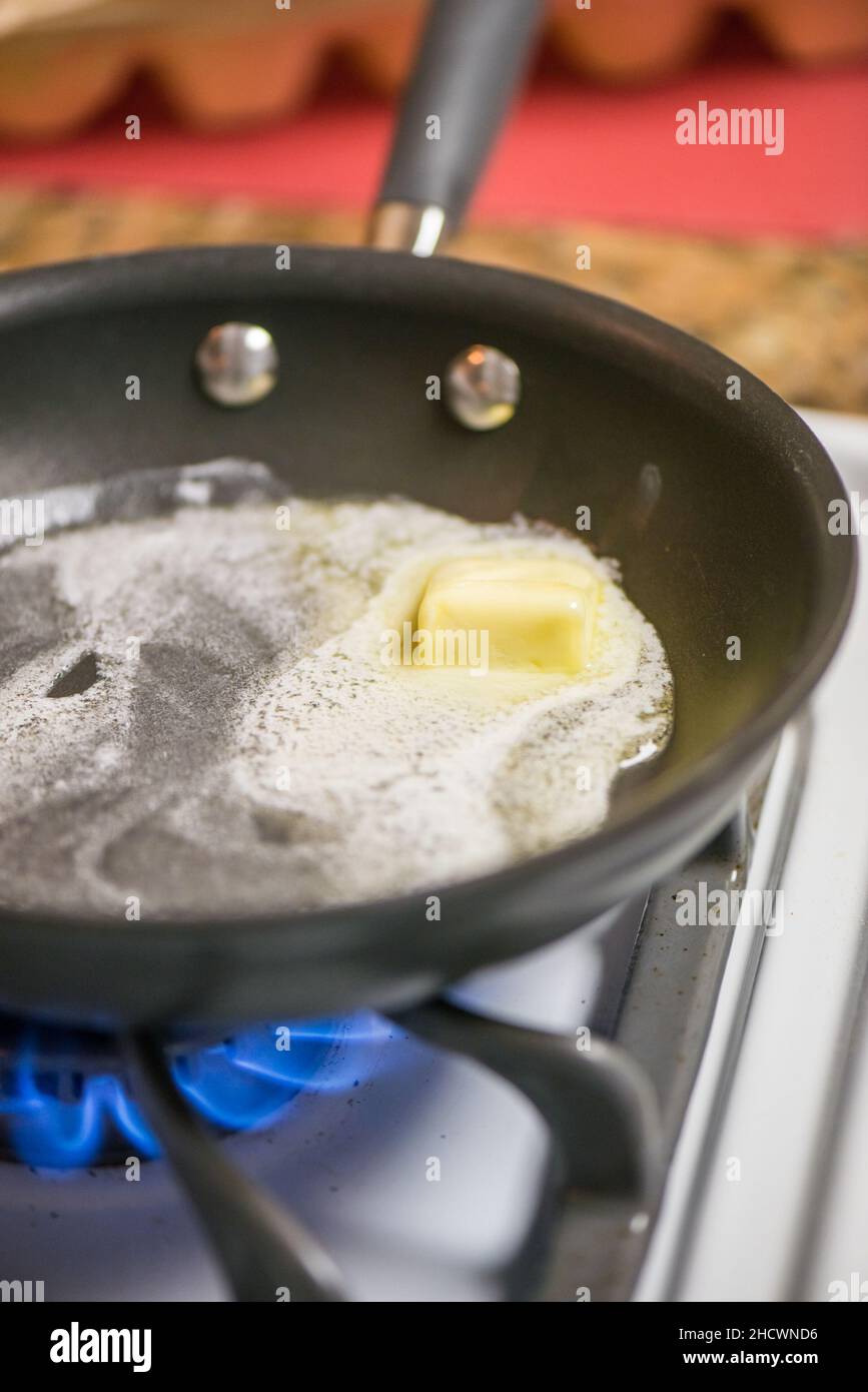 Il burro fuso in una padella sulla stufa con una fiamma a gas Foto ...