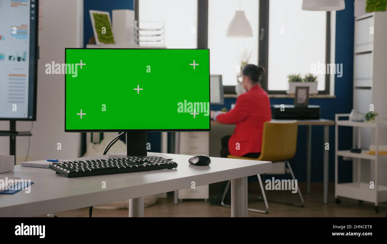 Schermo verde sul computer dell'ufficio aziendale. Scrivania vuota con ...
