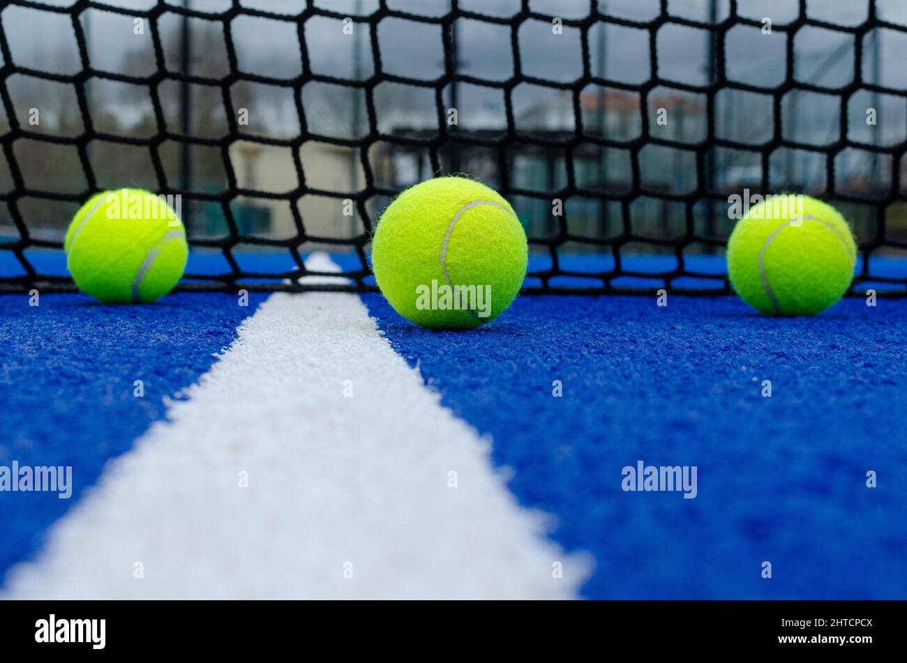 Rete di un campo da paddle tennis blu e tre palline vicino alla linea ...